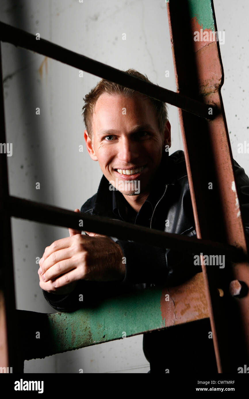 Smiling man leaning on ladder Stock Photo - Alamy