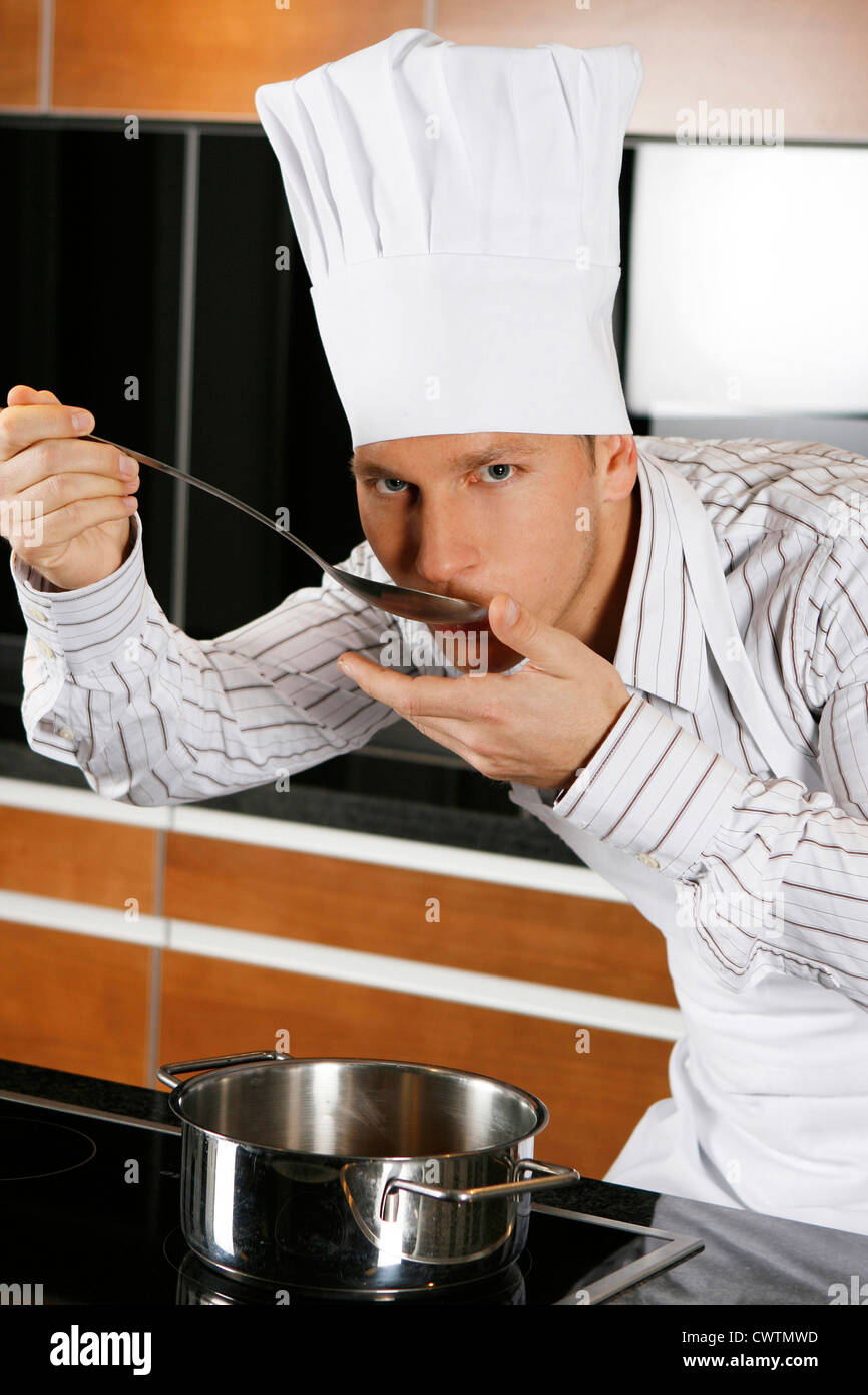 Cook in kitchen tasting food Stock Photo - Alamy