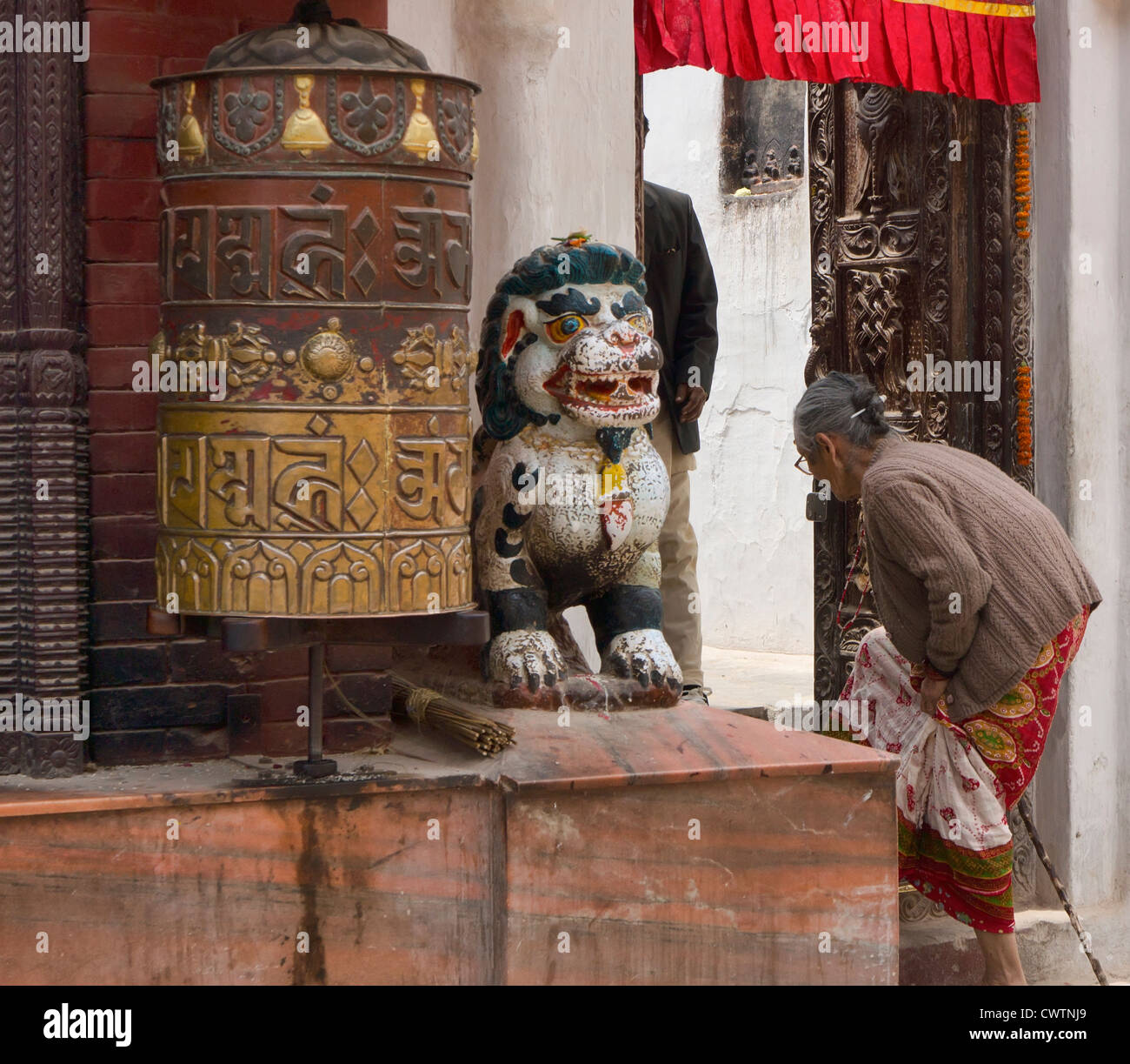 an old woman enters the temple at the Boudhanath in Kathmandu, Nepal ...
