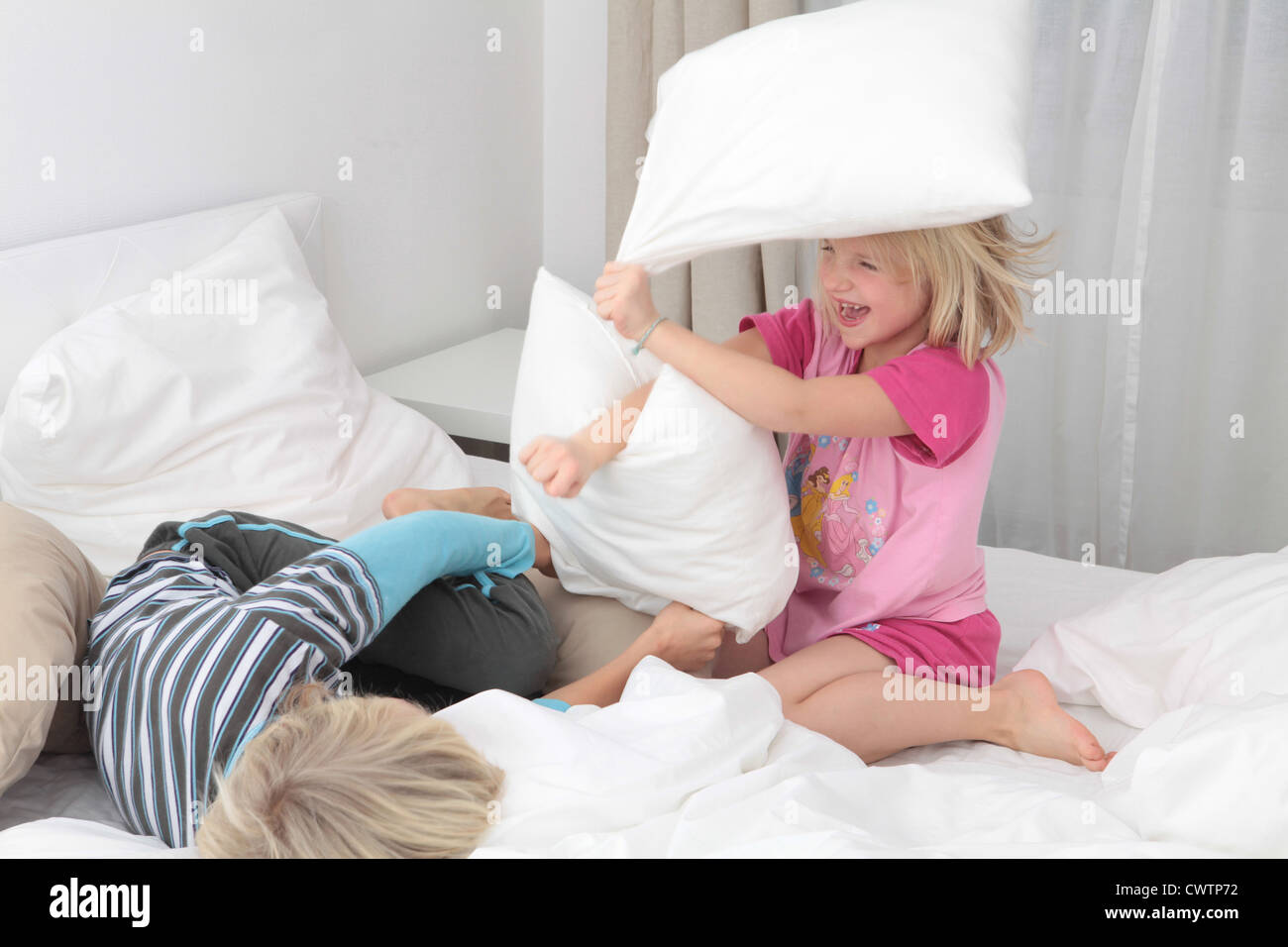 Brother and sister having a pillow fight in bed Stock Photo - Alamy