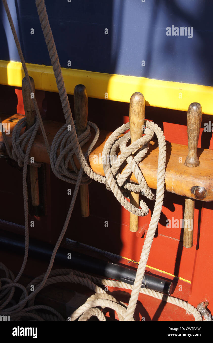 Coiled rope lines stored on belaying pins on a wooden tall ship Stock ...