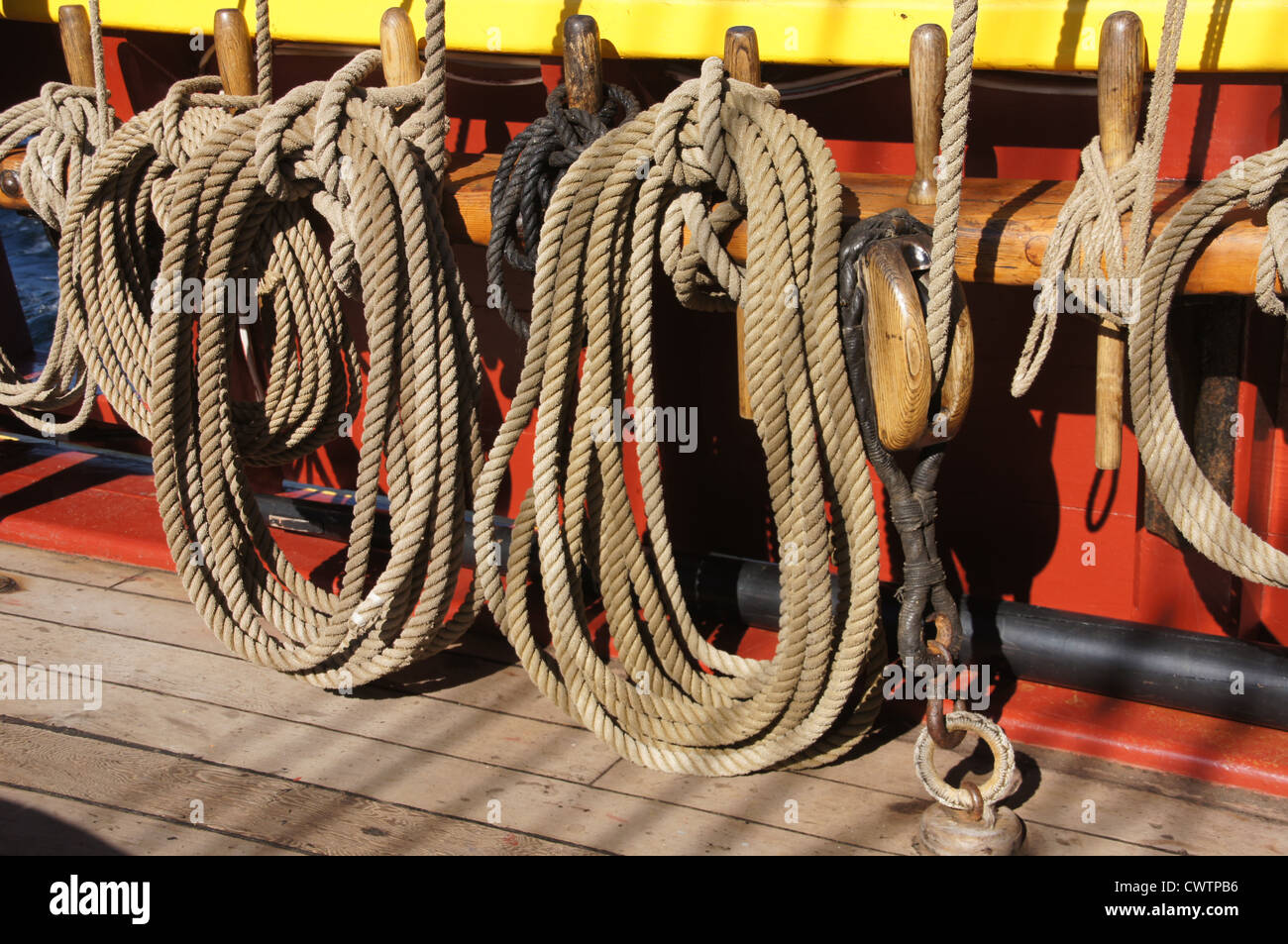 Coiled rope lines stored on belaying pins on a wooden tall ship Stock ...