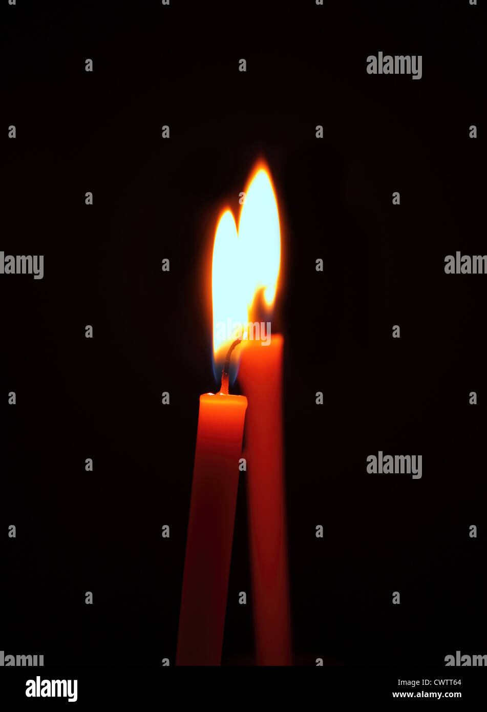 two burning candles on a black background Stock Photo - Alamy