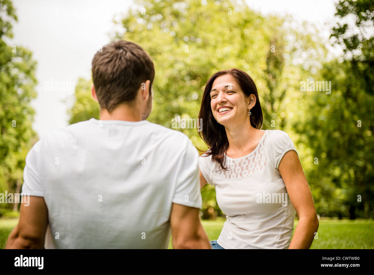 Young happy couple talking together outdoor - sitting on grass Stock ...