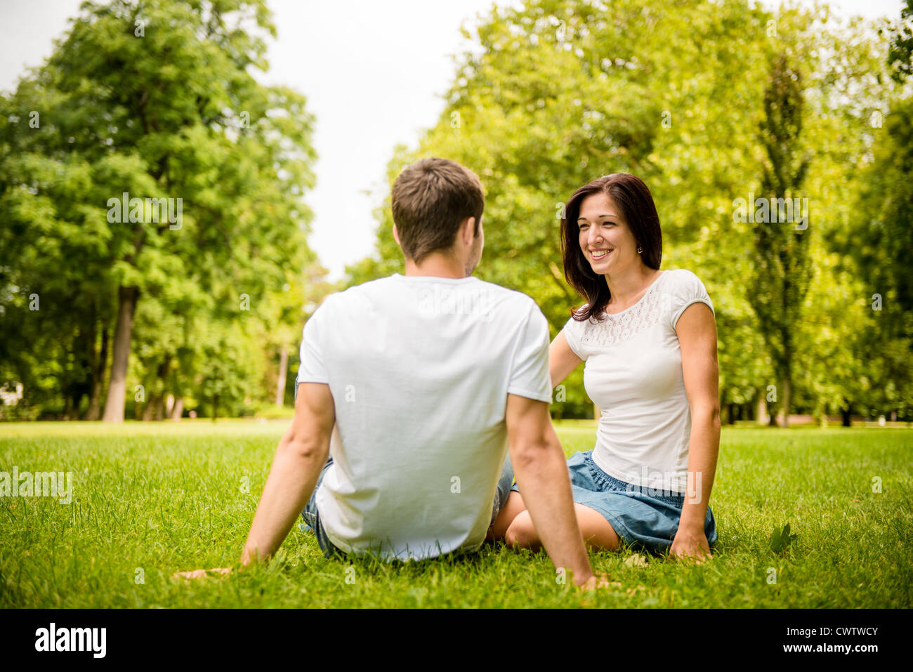 Young happy couple talking together outdoor - sitting on grass Stock ...