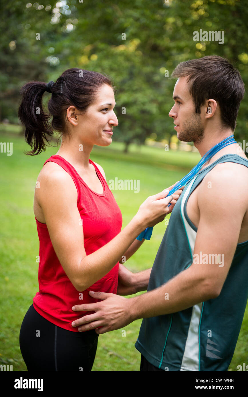 Young happy fitness couple kissing - woman put skipping rope around men ...