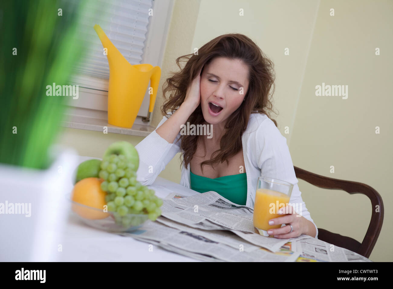 Young woman yawning at breakfast table Stock Photo - Alamy