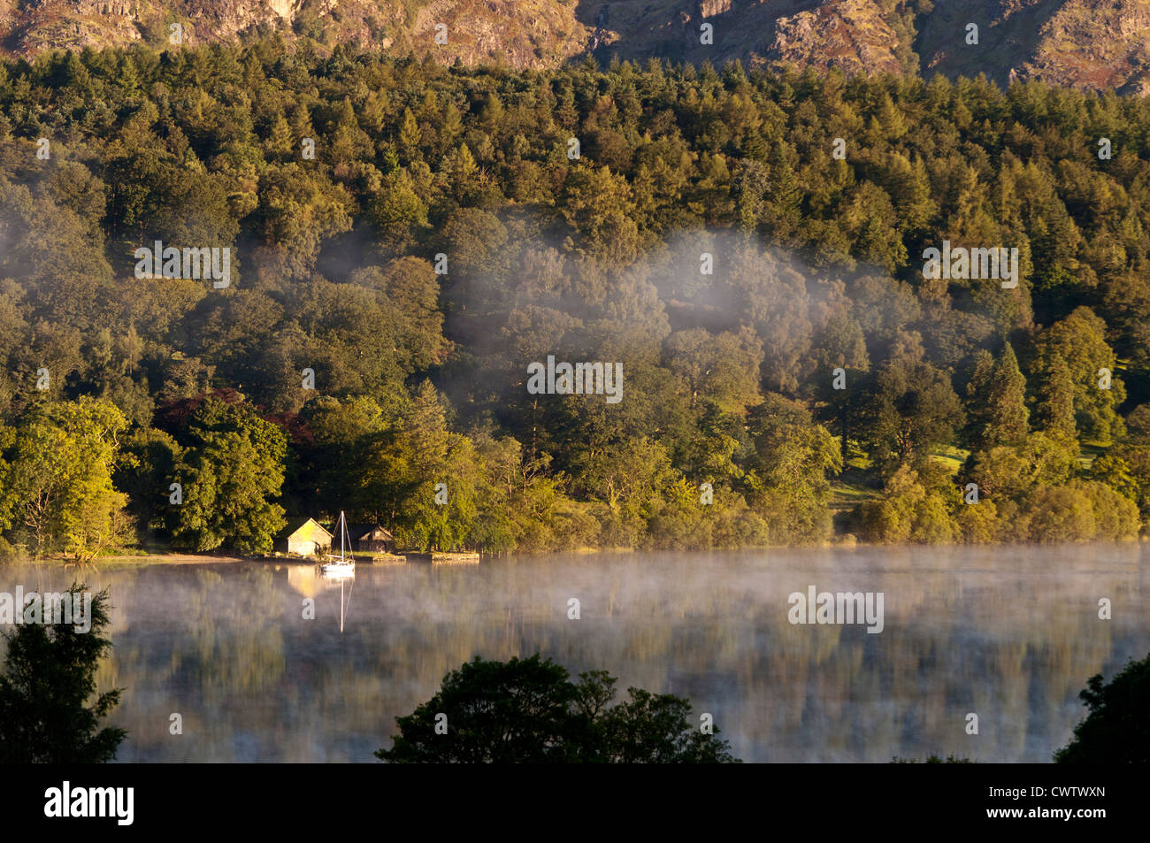 morning mist on Coniston water with boat and boathouse at Waterhead ...