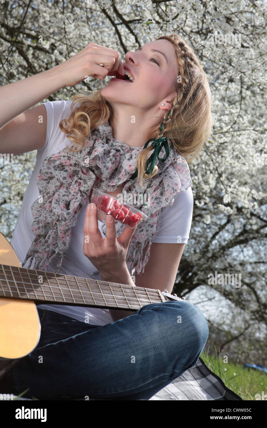 Happy woman eating raspberries at blooming tree Stock Photo - Alamy