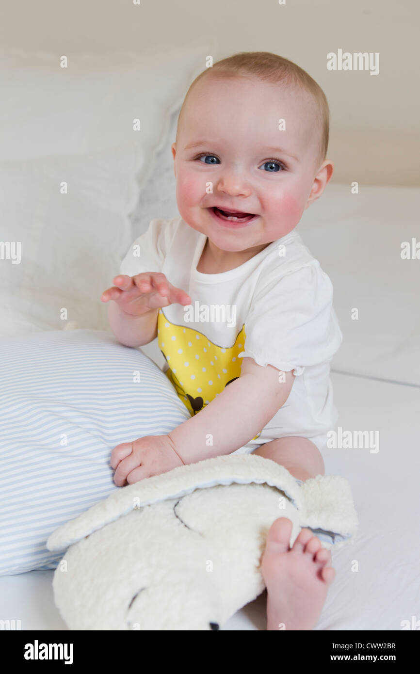 Smiling baby sitting on bed Stock Photo - Alamy