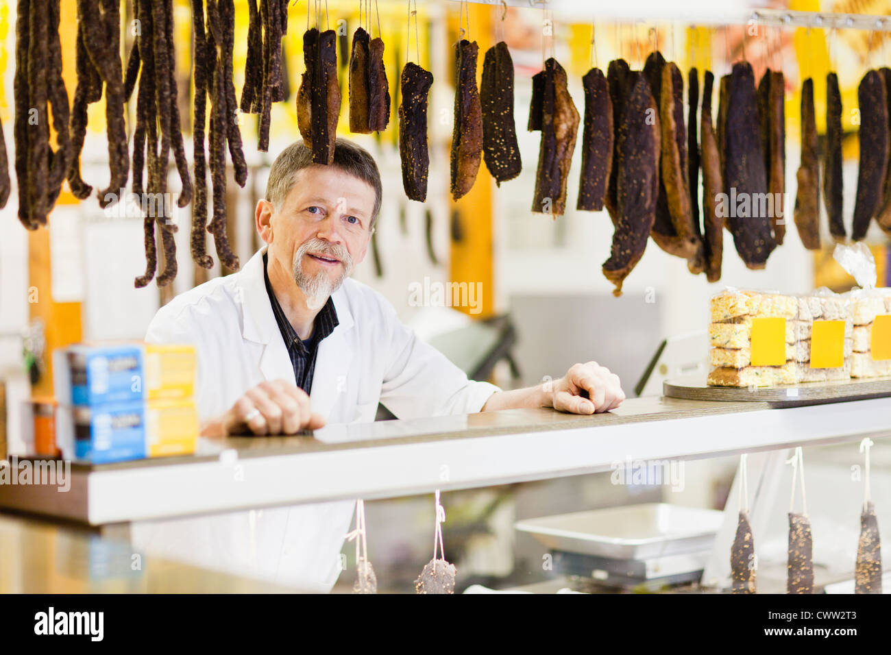 Butcher standing at meat counter Stock Photo - Alamy