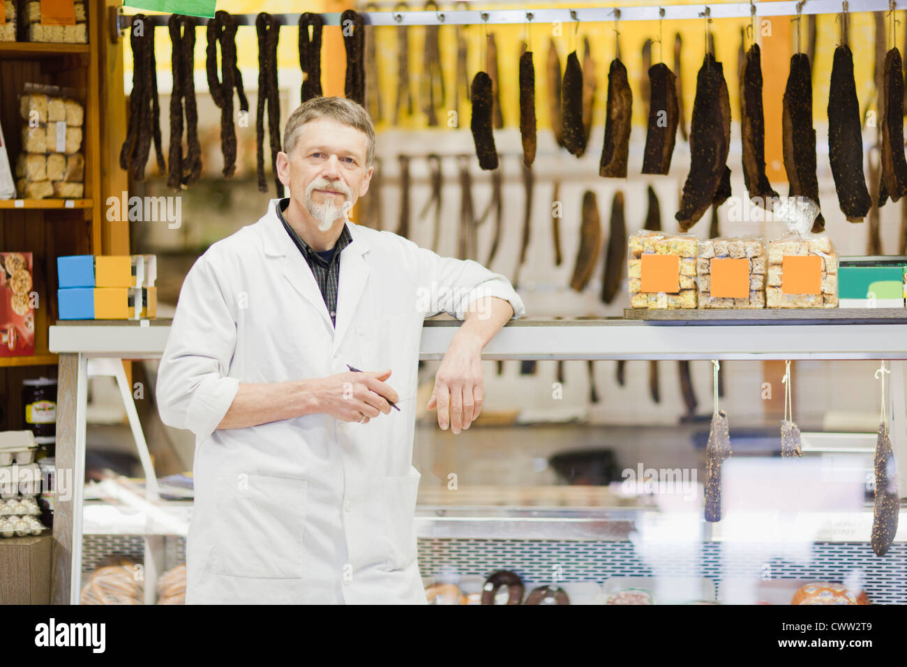 Butcher standing at meat counter Stock Photo - Alamy