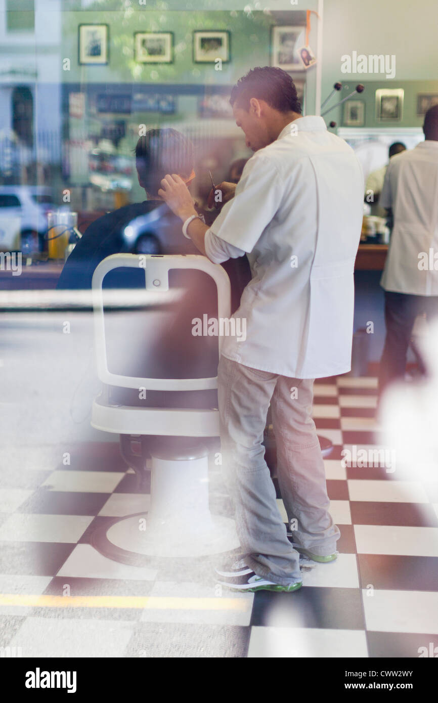 Barber working on client in shop Stock Photo - Alamy