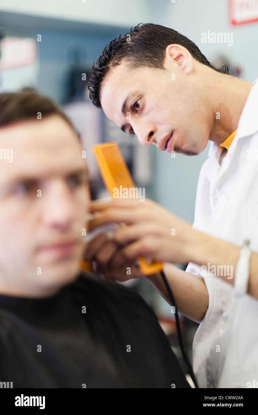 Barber working on client in shop Stock Photo - Alamy