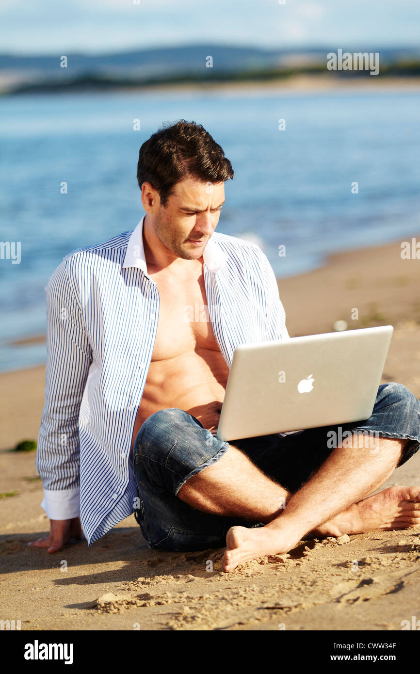 Man relaxing on beach with laptop Stock Photo - Alamy