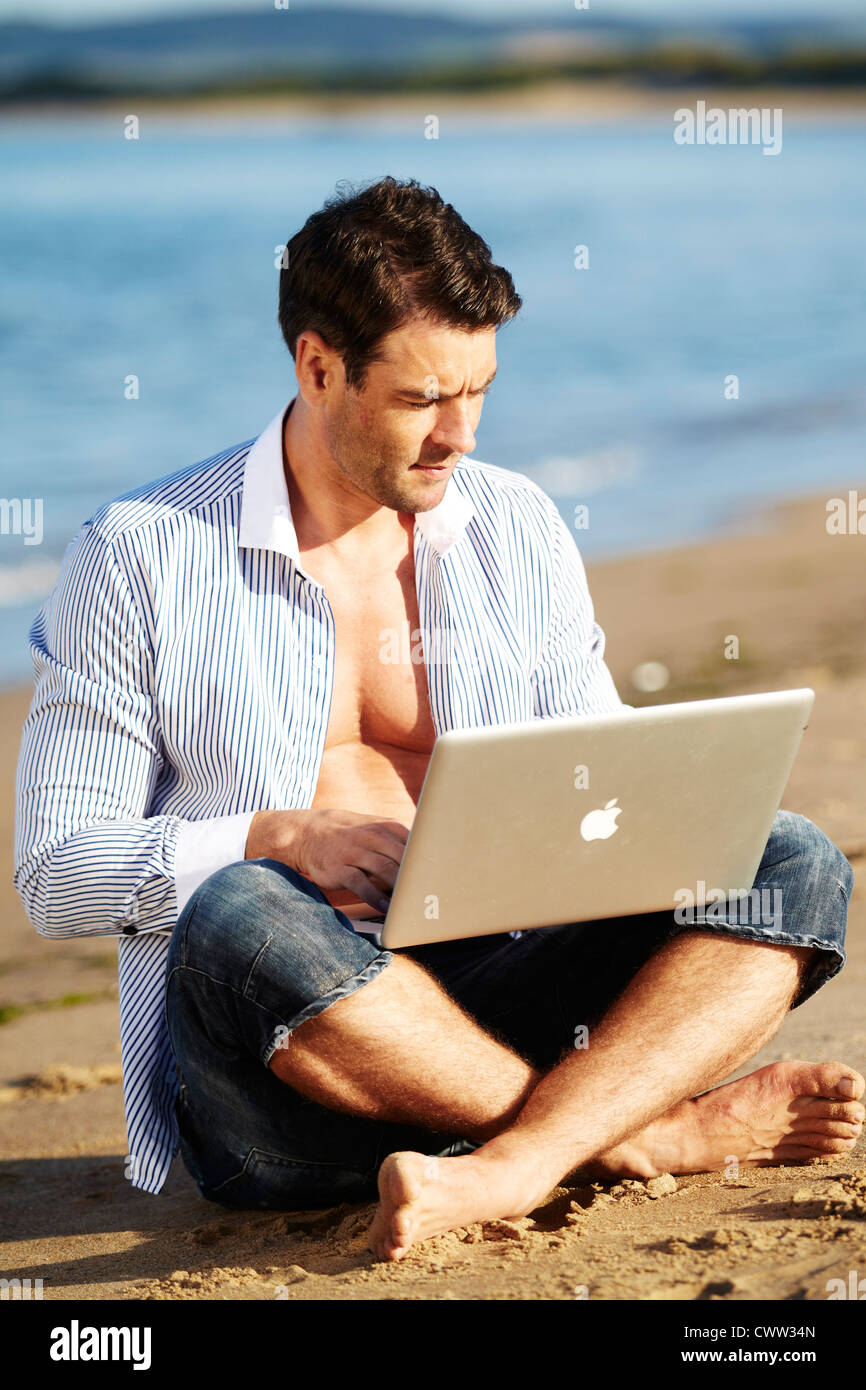 Man relaxing on beach with laptop Stock Photo - Alamy