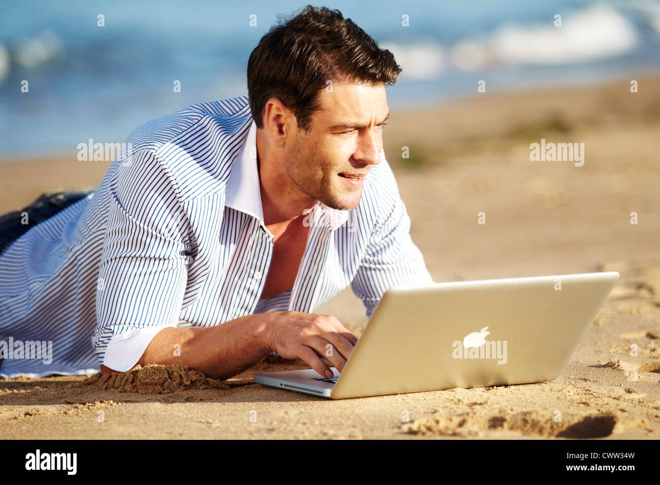 Man relaxing on beach with laptop Stock Photo - Alamy