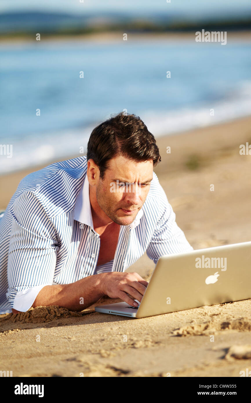 Man relaxing on beach with laptop Stock Photo - Alamy