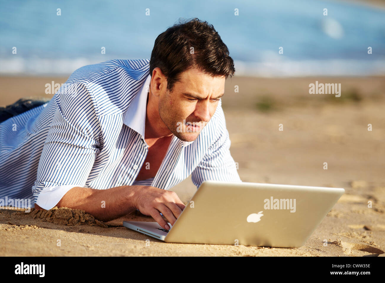 Man relaxing on beach with laptop Stock Photo - Alamy
