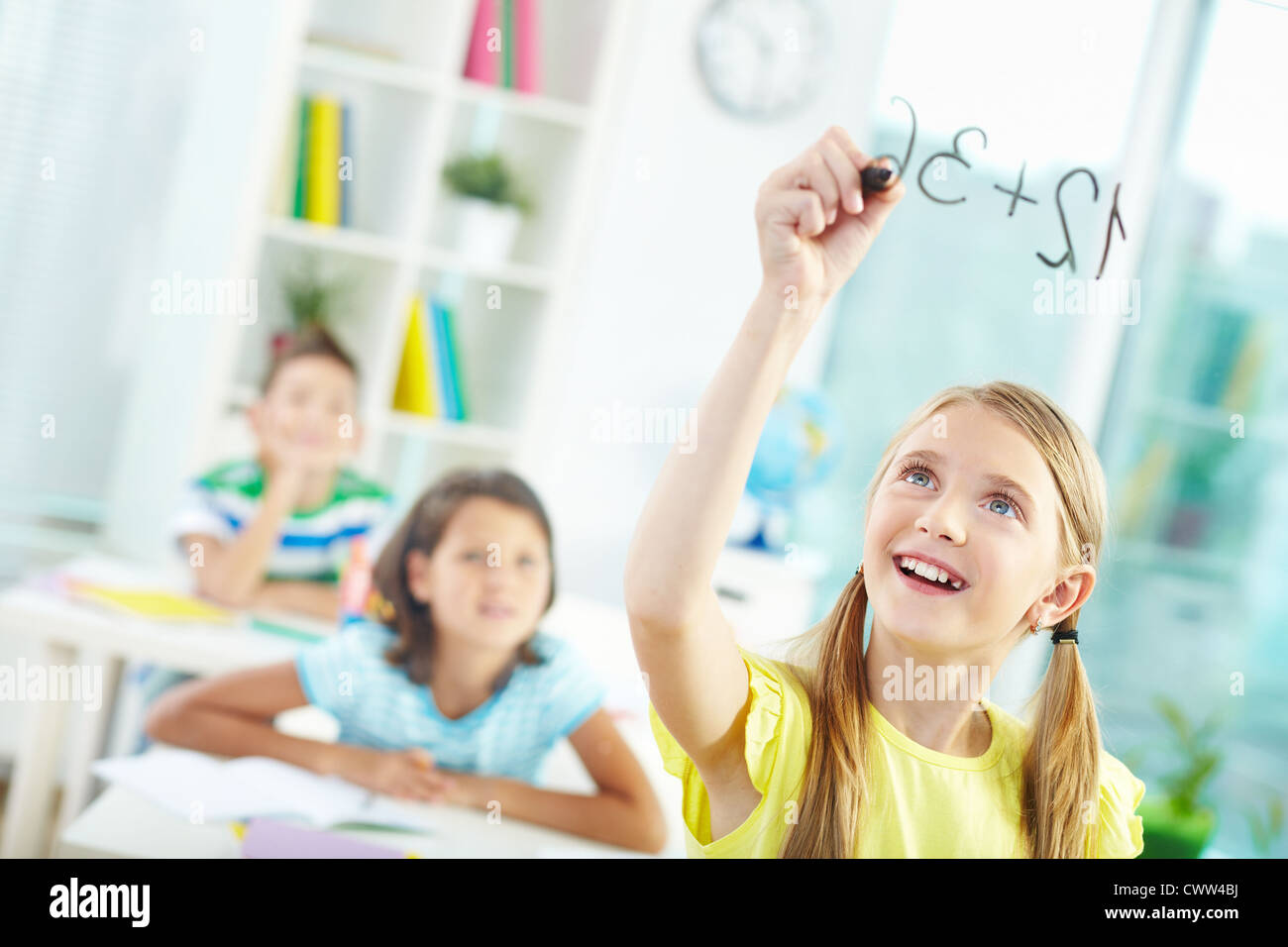Portrait of lovely girl doing sums on transparent board with ...