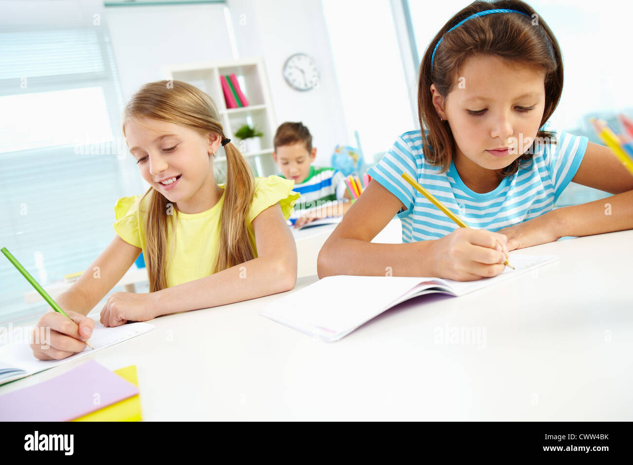 Portrait of lovely schoolgirls drawing at workplace with schoolmate on ...