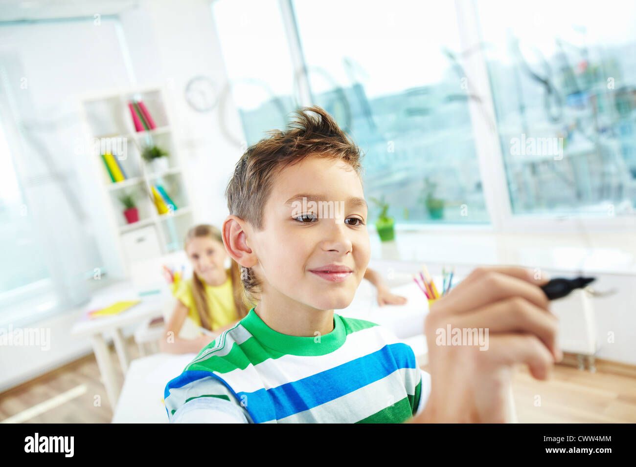 Portrait of clever boy doing sums on transparent board with schoolmate ...