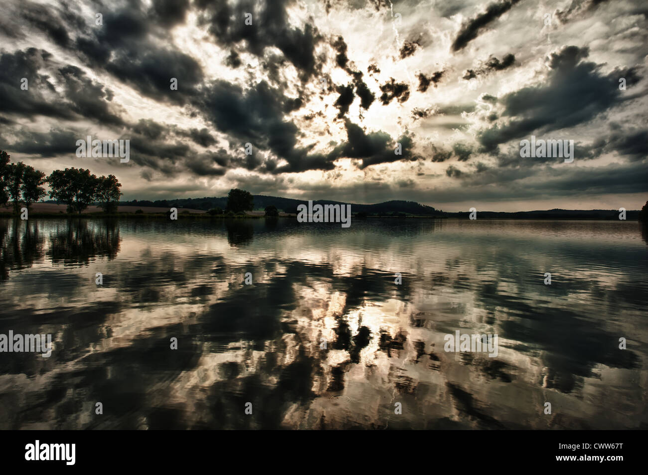 Very dramatic sunset is being reflected in the large lake. Dark deep ...