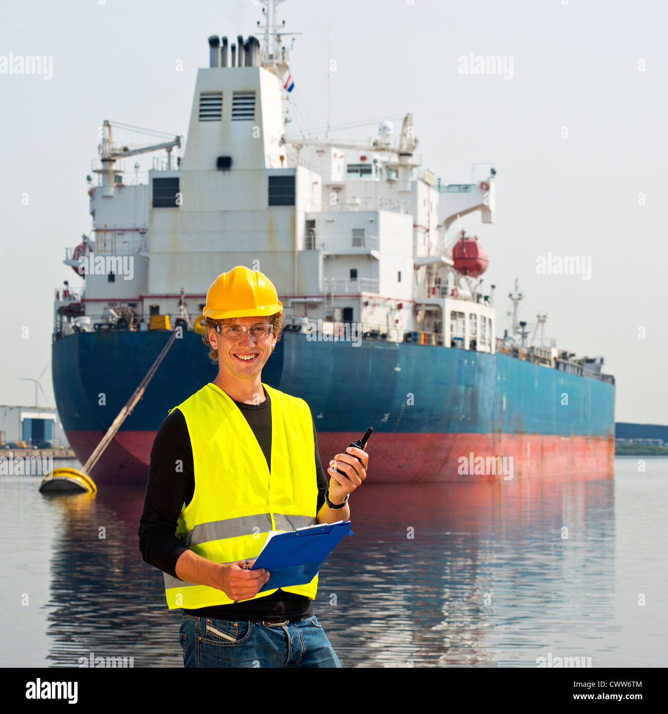 Smiling docker with clipboard and cb radio, posing in front of a large ...