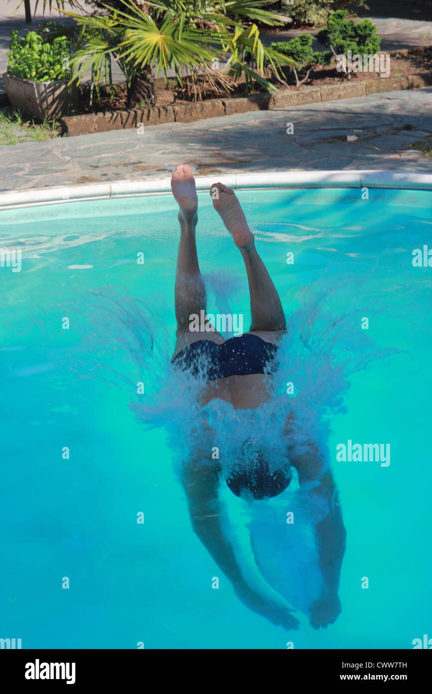 Diving into a swimming pool with head in the water and feet still in ...