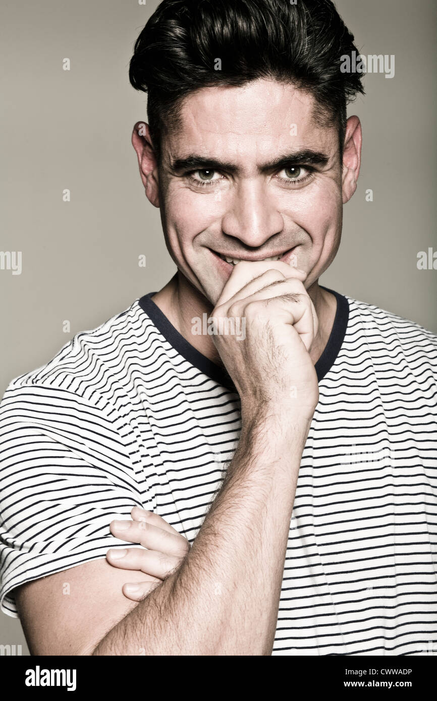 Smiling man biting his finger Stock Photo - Alamy