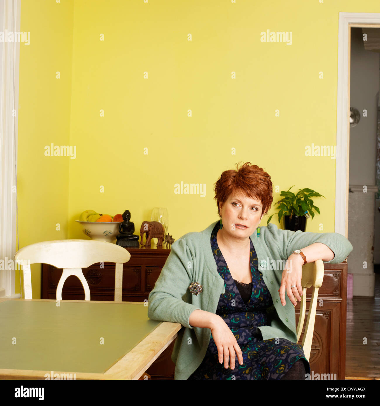 Woman sitting at kitchen table Stock Photo - Alamy