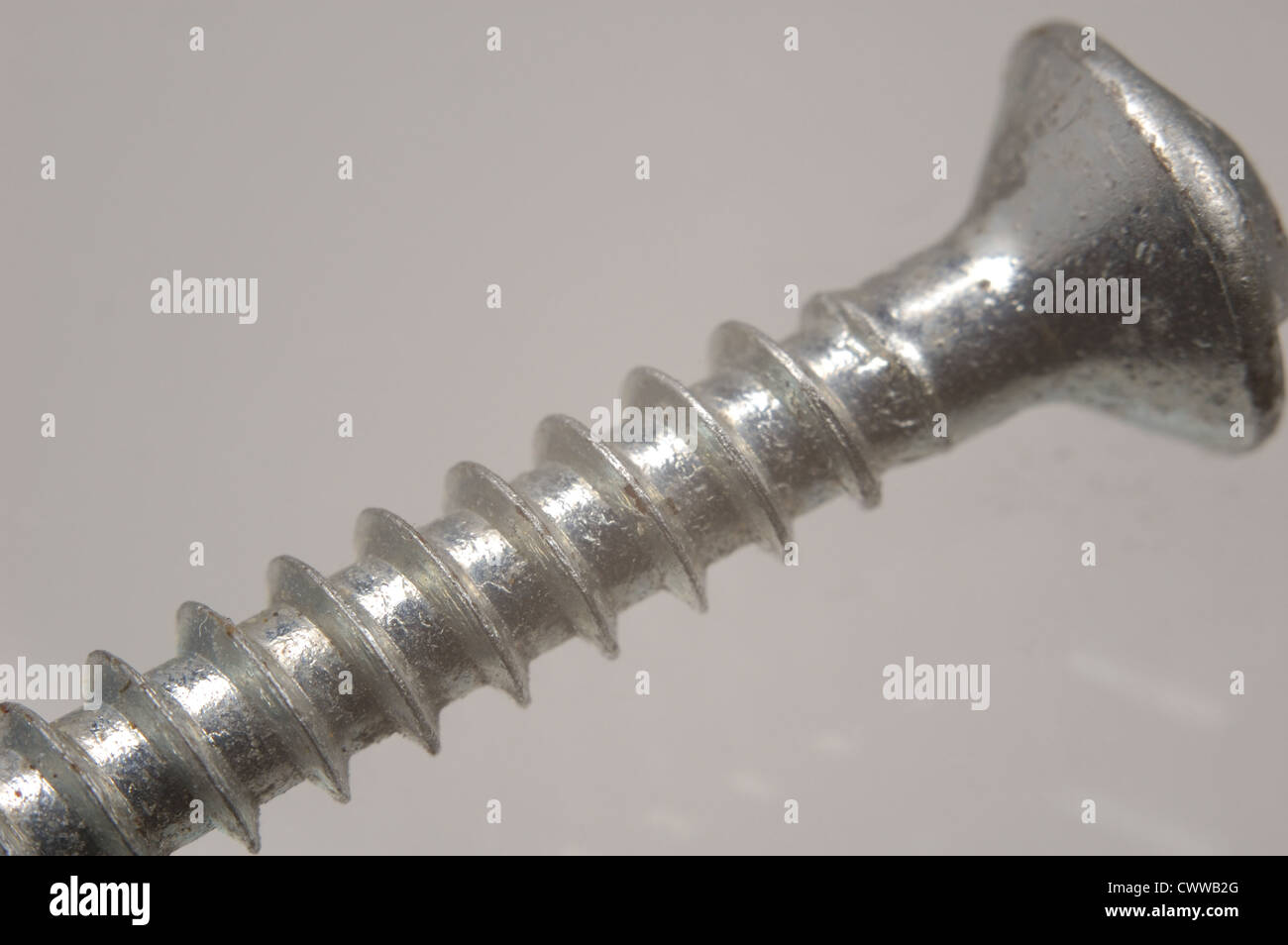 Close up detail of screw against a grey background Stock Photo - Alamy