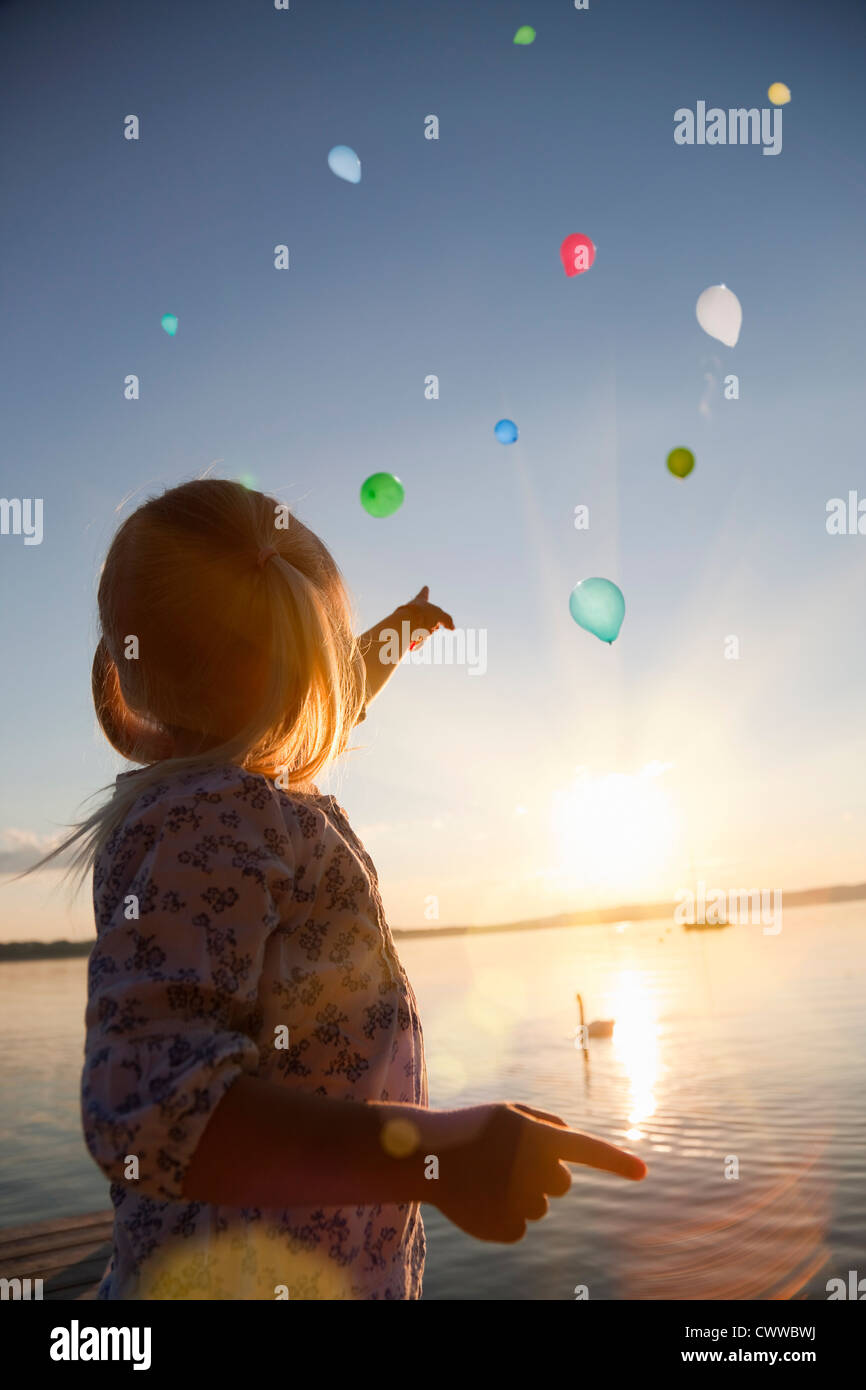 Girl watching balloons floating away Stock Photo - Alamy