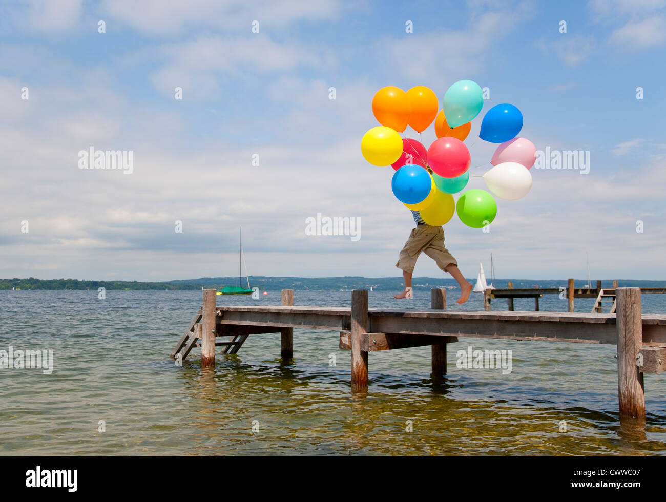Boy holding balloons on wooden pier Stock Photo - Alamy