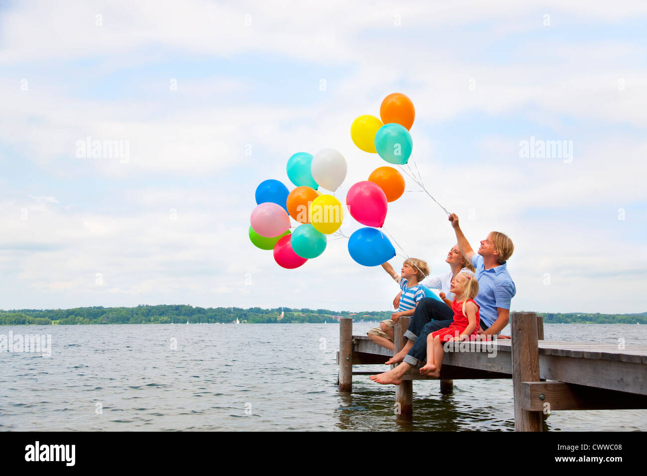 Family holding balloons on wooden pier Stock Photo - Alamy