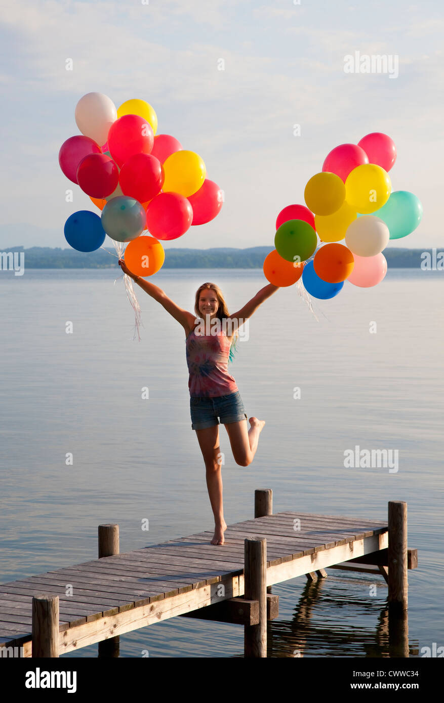 Teenage girl holding balloons on pier Stock Photo - Alamy