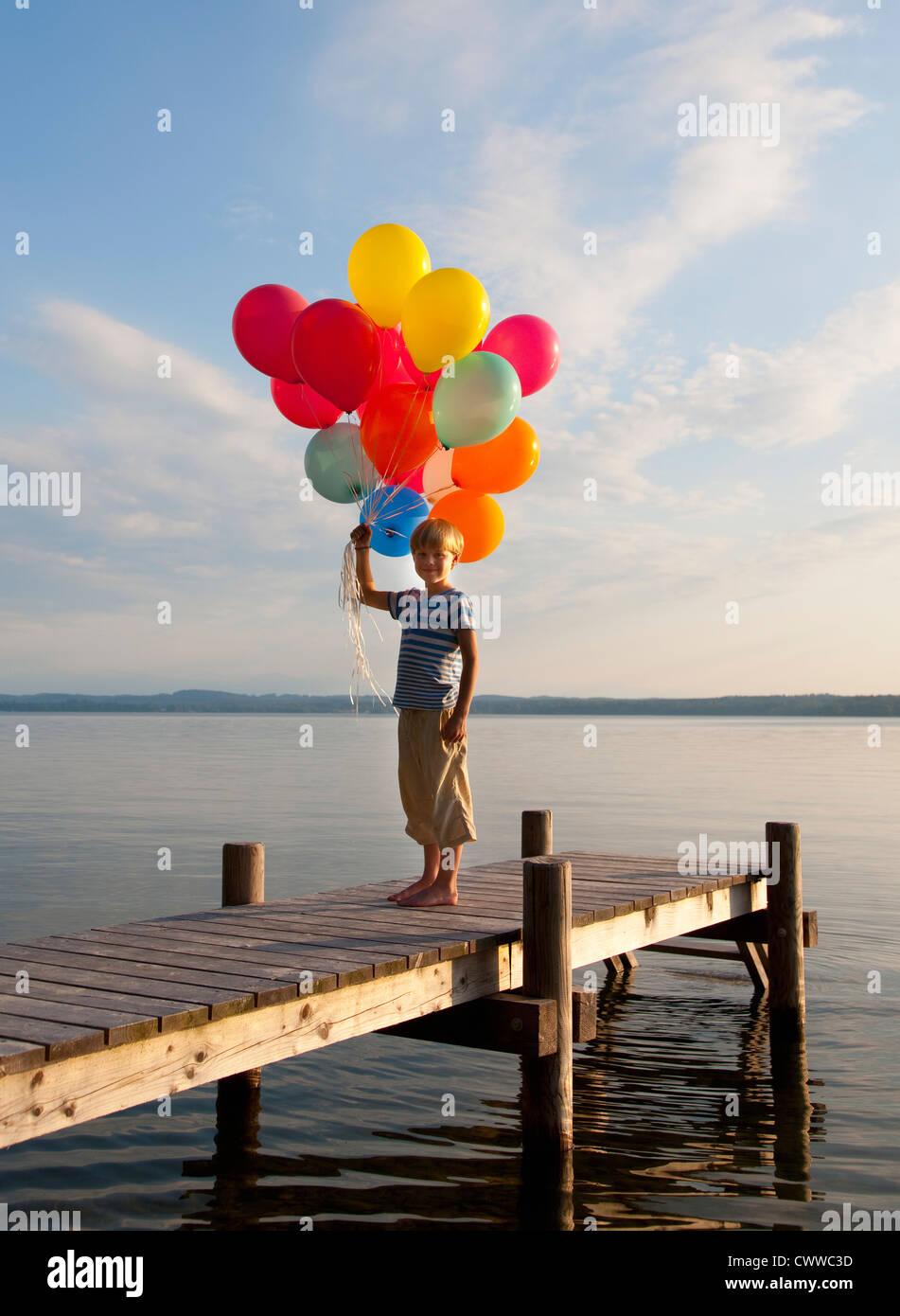 Boy holding balloons on wooden pier Stock Photo - Alamy