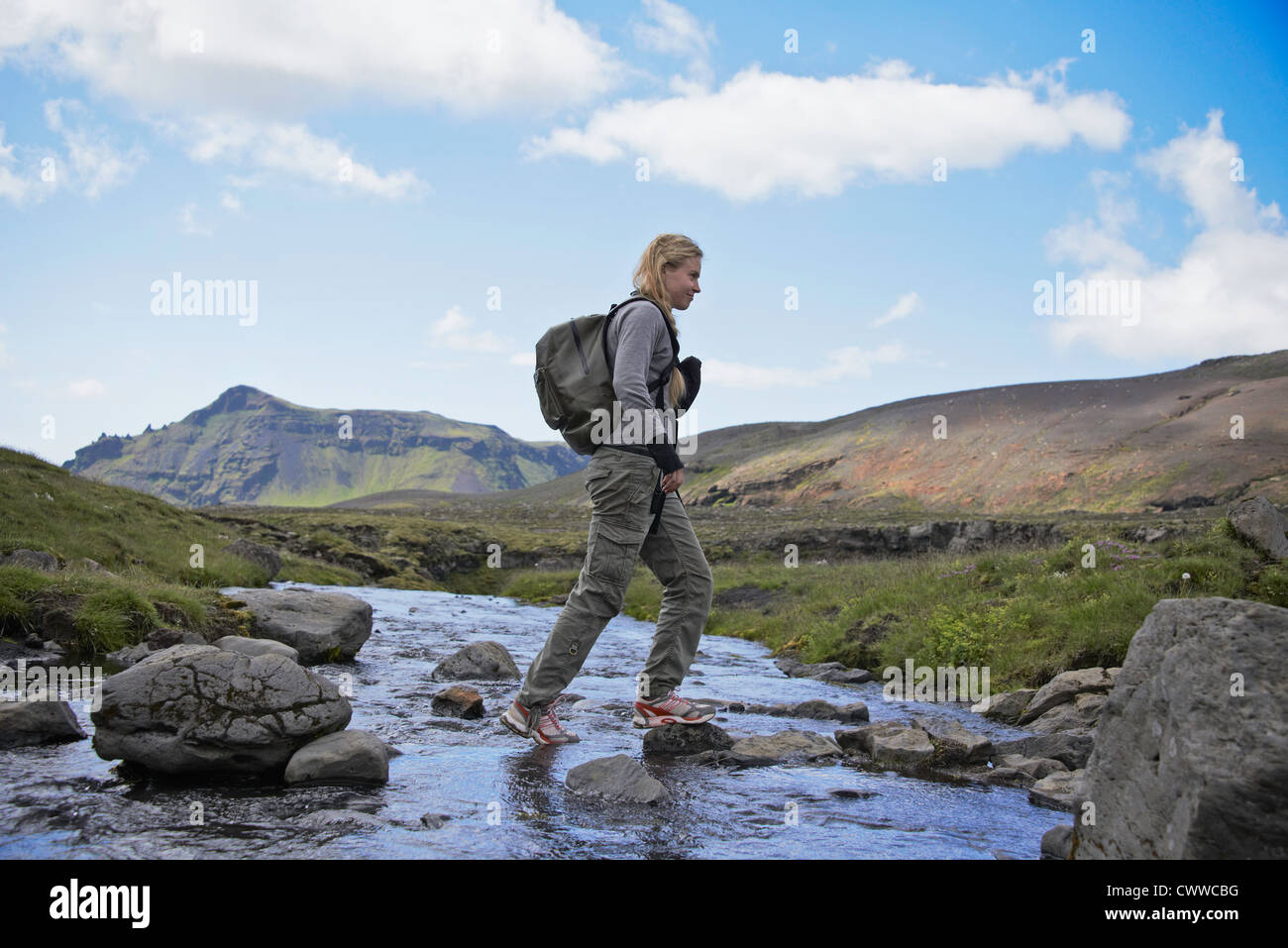 Hiker crossing rocky rural stream Stock Photo - Alamy