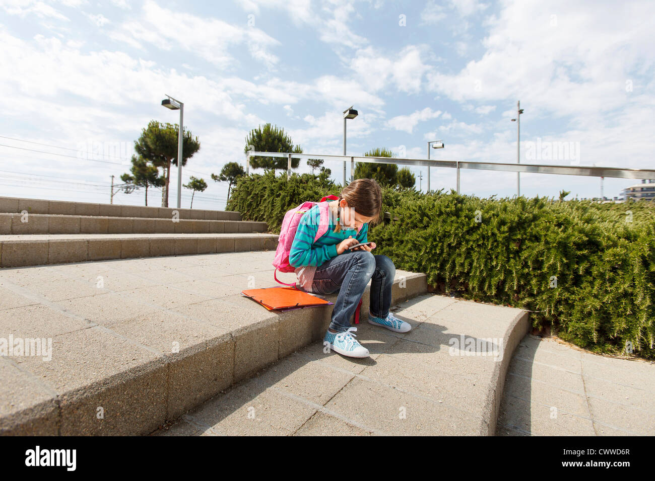 Girl using cell phone on steps outdoors Stock Photo - Alamy
