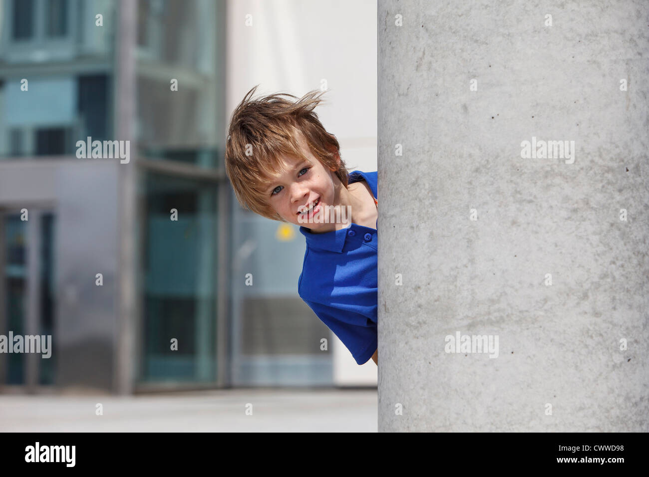 Boy peering out from behind column Stock Photo - Alamy
