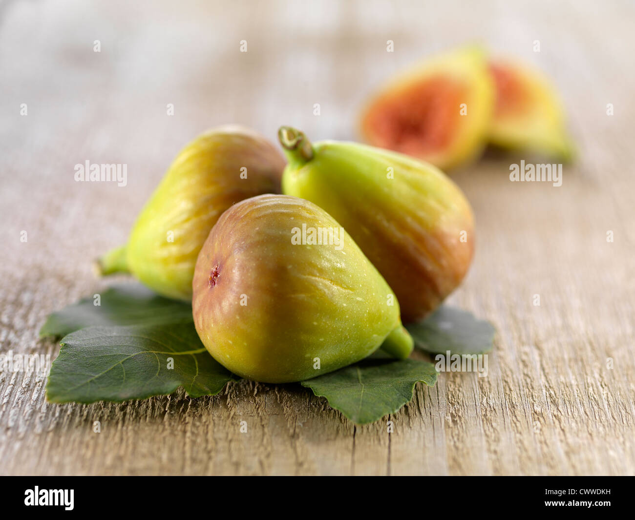 three figs with leaves on rustic table Stock Photo - Alamy