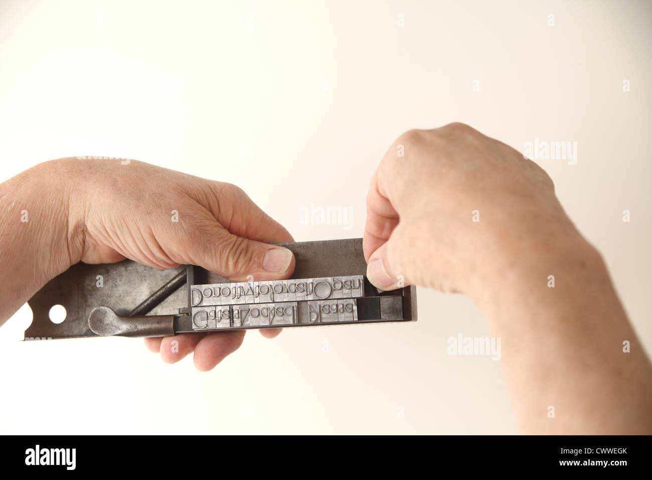 a printer adjusts letterpress metal type on a tool used to set type ...