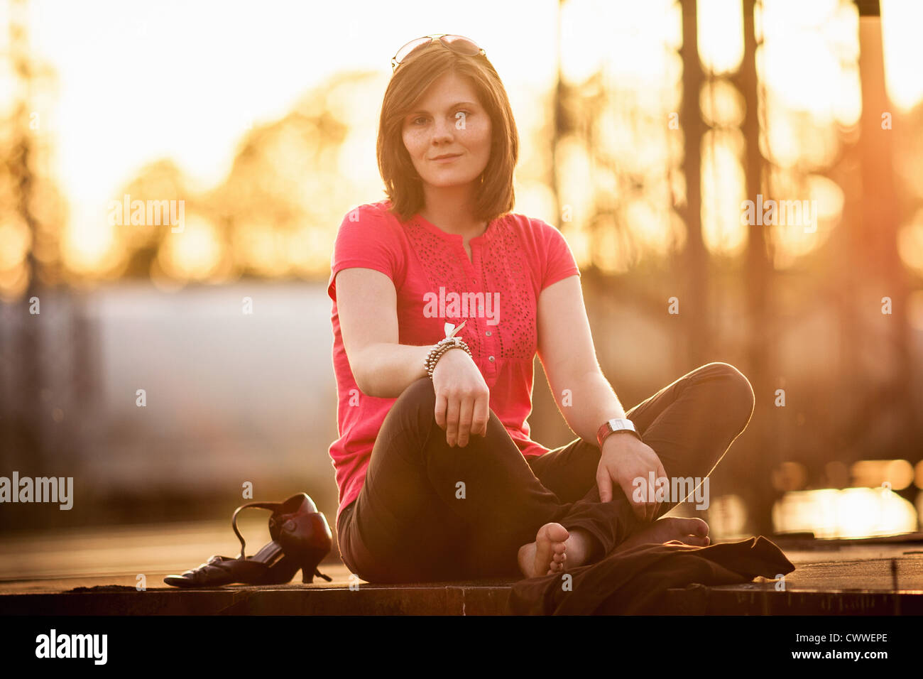 Woman sitting cross-legged on stone wall Stock Photo - Alamy