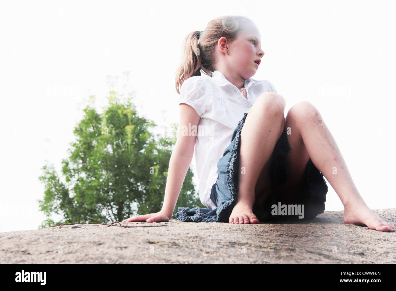 Girl sitting on stone wall Stock Photo - Alamy