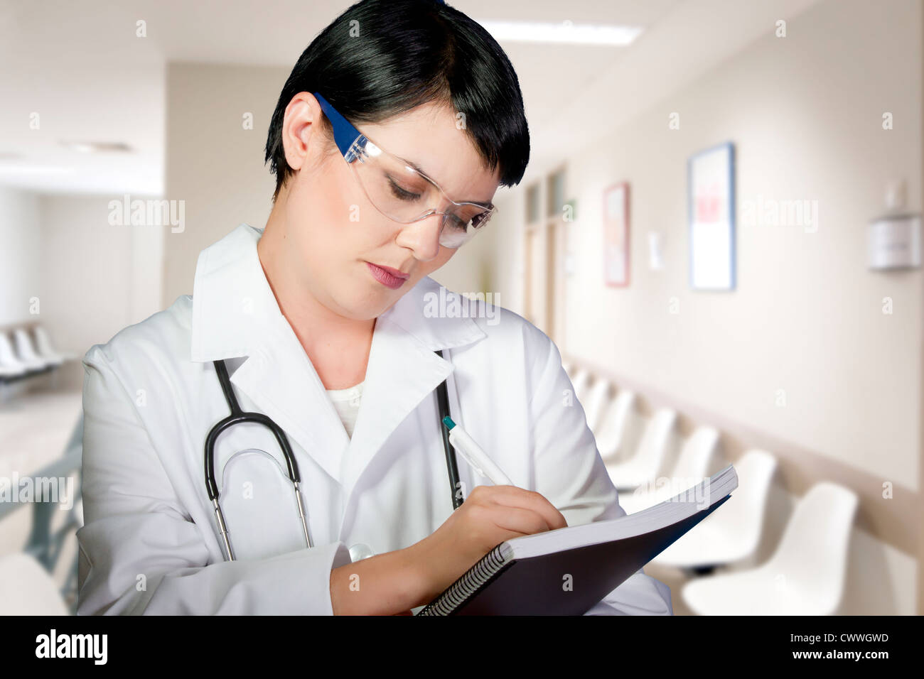 thoughtful brunette female doctor on duty at the ER lobby taking notes ...