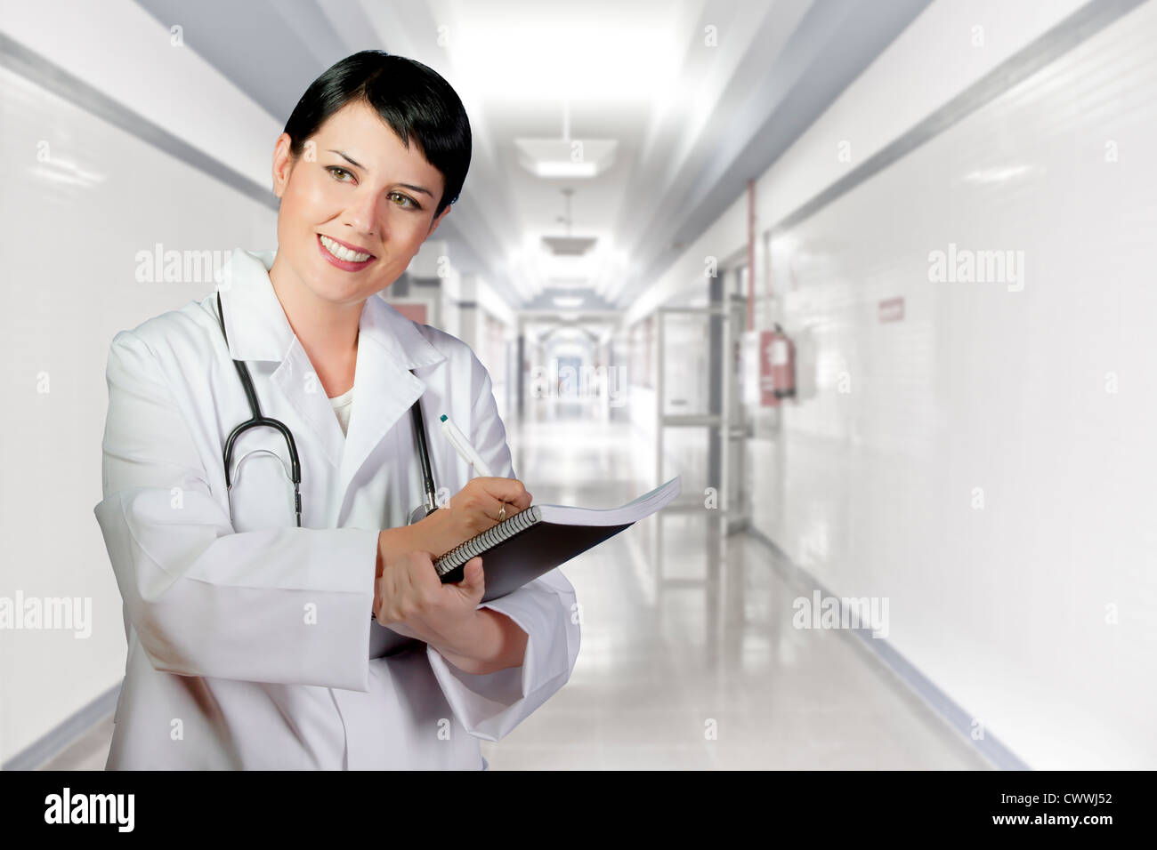 brunette female doctor on duty at white hospital corridor, PHD and ...