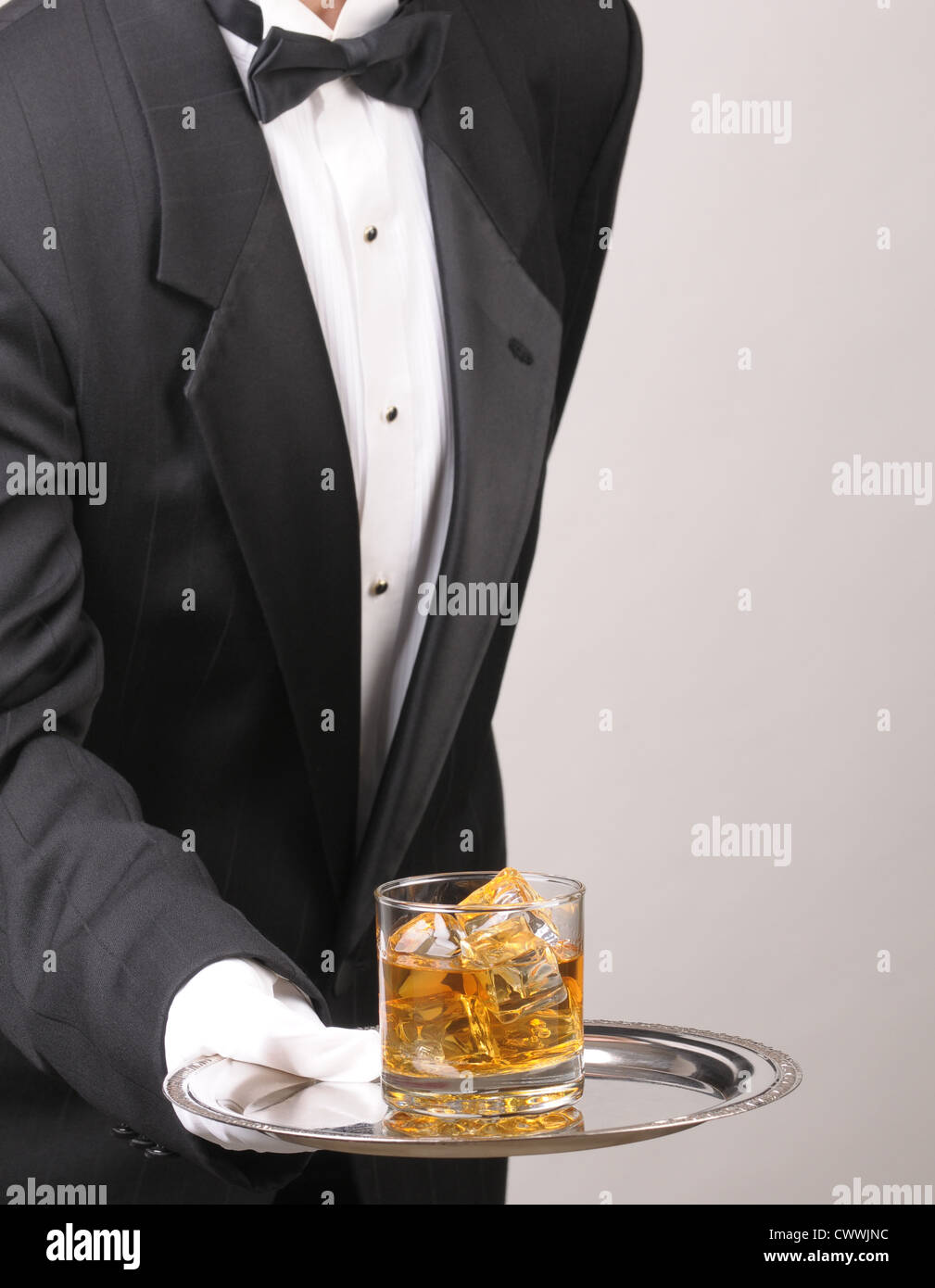 Waiter in tuxedo Presenting Cocktail on silver tray vertical format ...