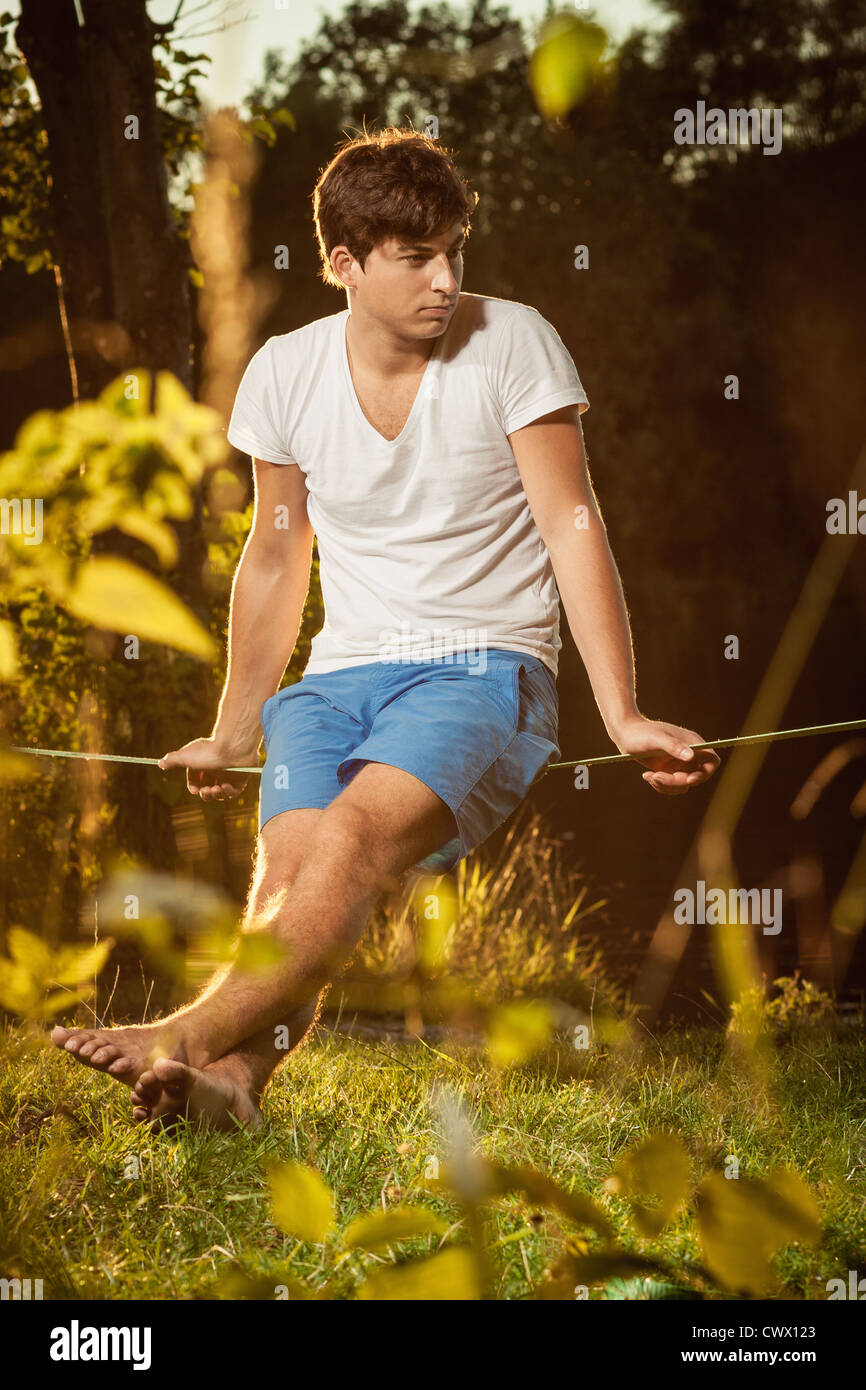 Man sitting on tight rope outdoors Stock Photo - Alamy