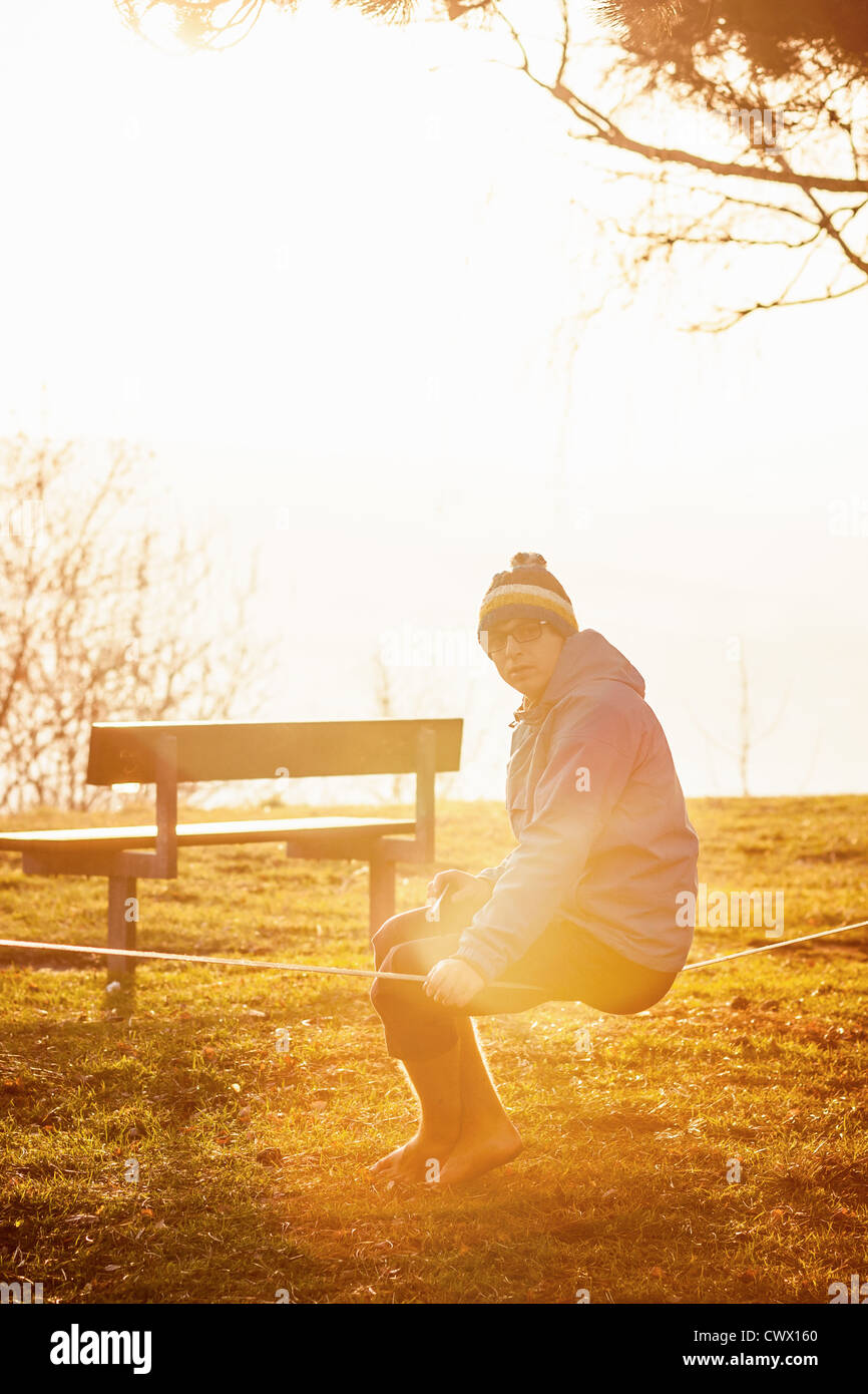 Man sitting on tight rope outdoors Stock Photo - Alamy