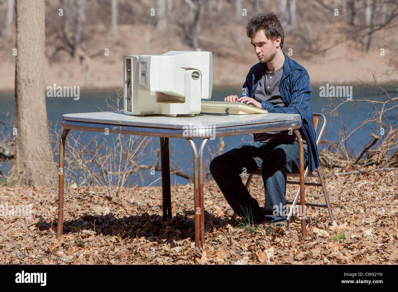 A Young Man typing on his Computer in the Outdoors and surrounded by ...